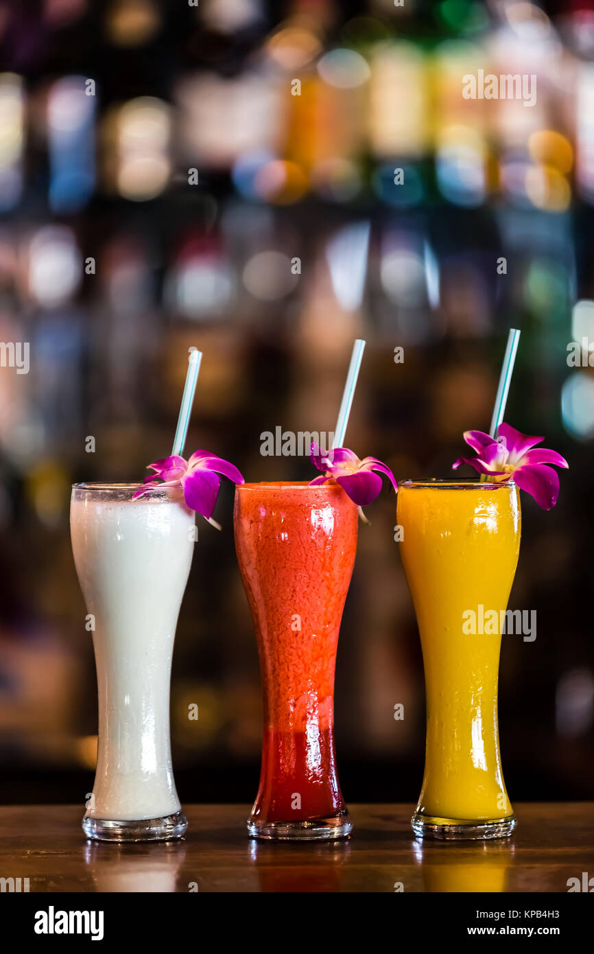 Vertical composition with 3 yellow, white, red cocktails and orchid ...