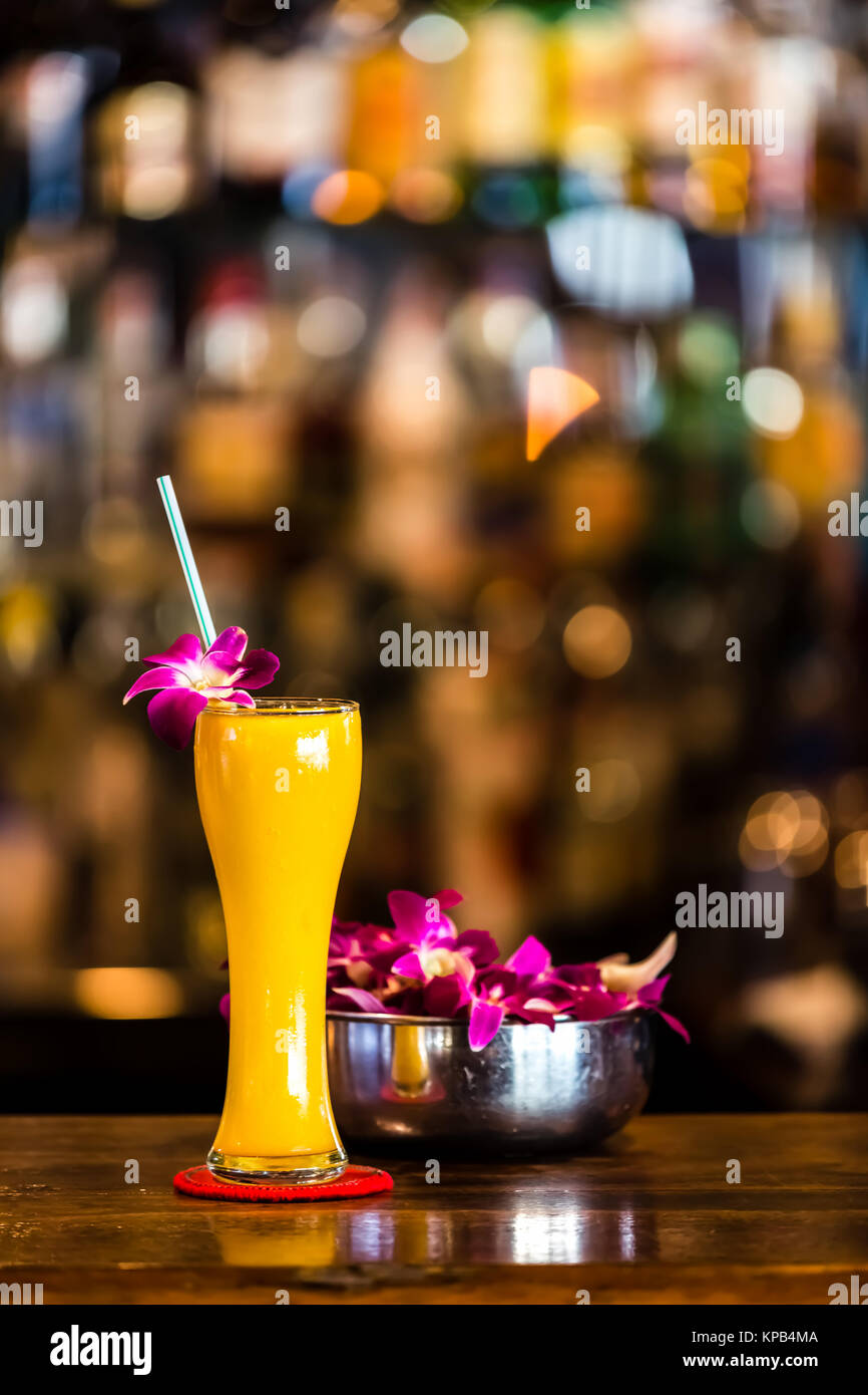 Yellow cocktail with orchid flower in the bar on the blurred background ...