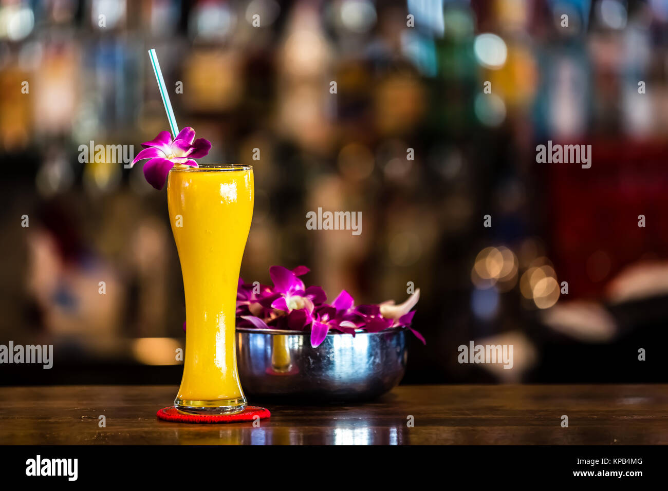 Yellow cocktail with orchid flower in the bar on the blurred background ...