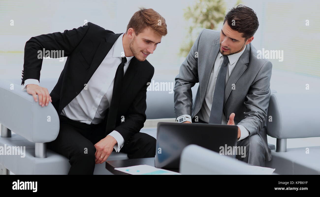 Smiling business men showing something on computer as colleague looking ...