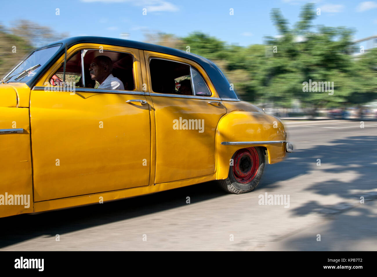 Motion shot of a vintage bright yellow car driving in Havana Cuba with ...