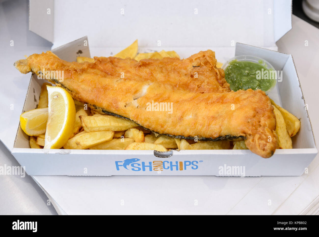 A Large Portion Of Traditional British Fish And Chips With Mushy Peas