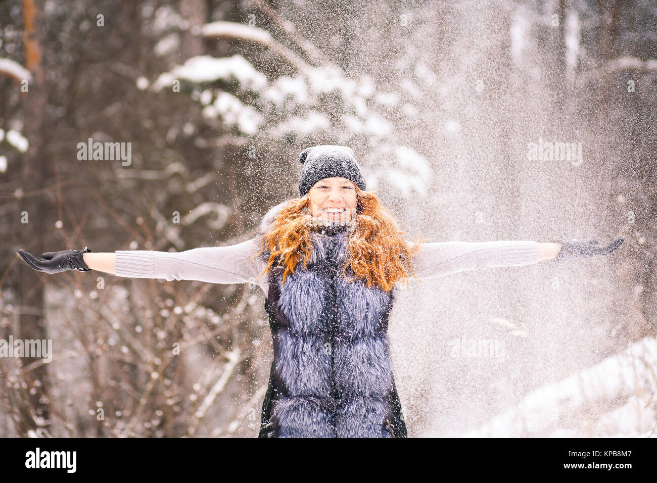 Winter fun. Girl in winter clothes throwing snow up in air. Young woman ...