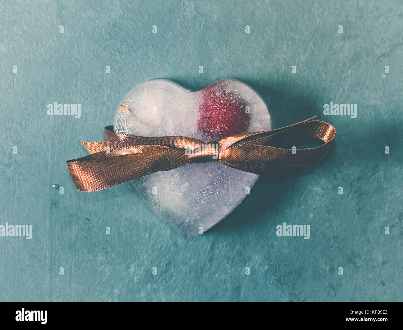 Heart shaped lavender syrup ice cubes with frozen cherry on blue ...