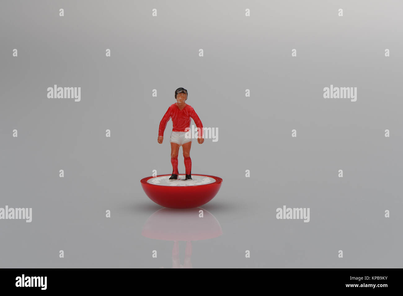 A single Subbuteo player in red kit on white background with copy space ...