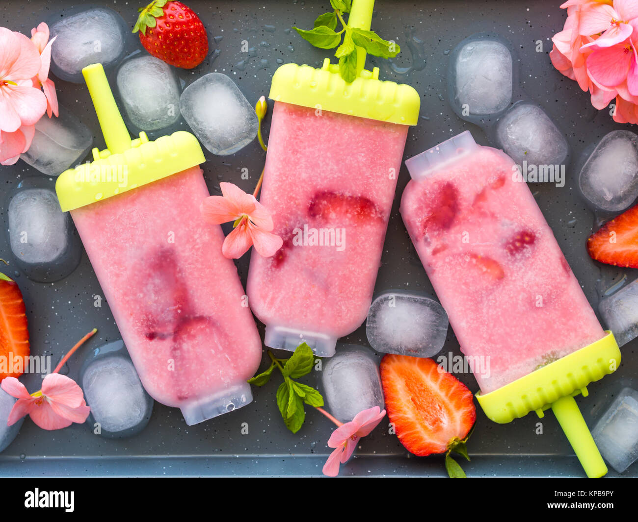 Home made strawberry ice cream popsicles on metall tray with ice cubes ...