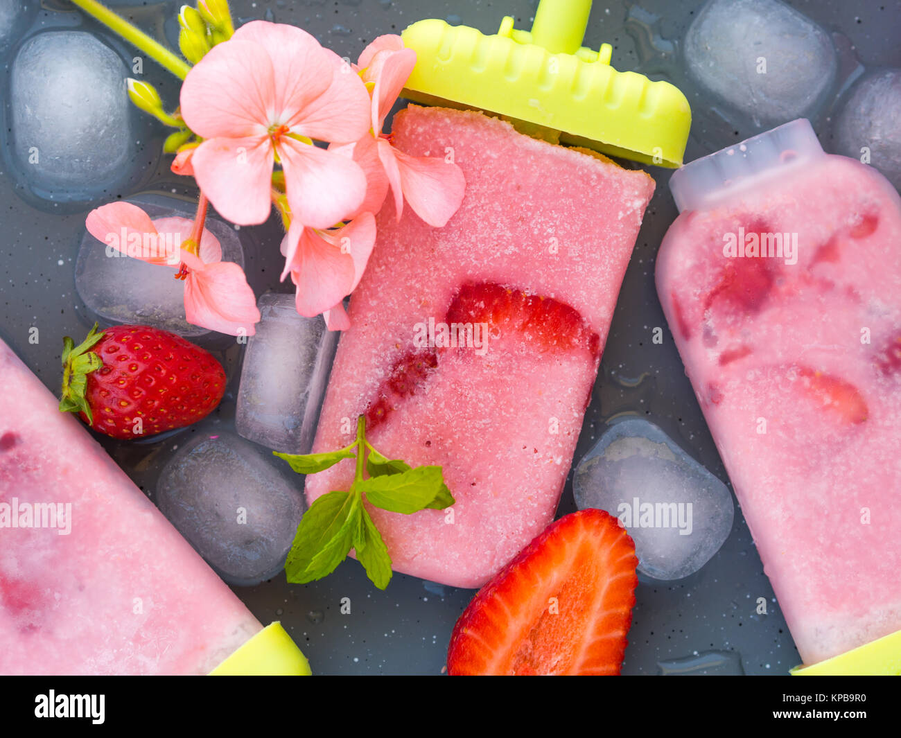Home made strawberry ice cream popsicles on metall tray with ice cubes ...