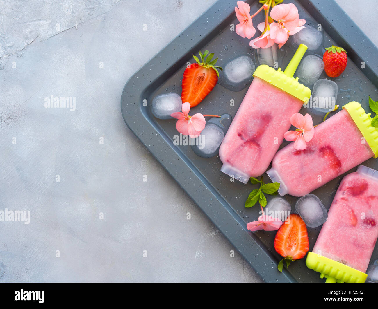 Home made strawberry ice cream popsicles on metall tray with ice cubes ...
