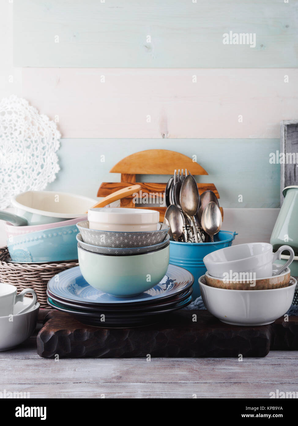 Ceramic and enamel crockery tableware on wooden background. Pastel ...