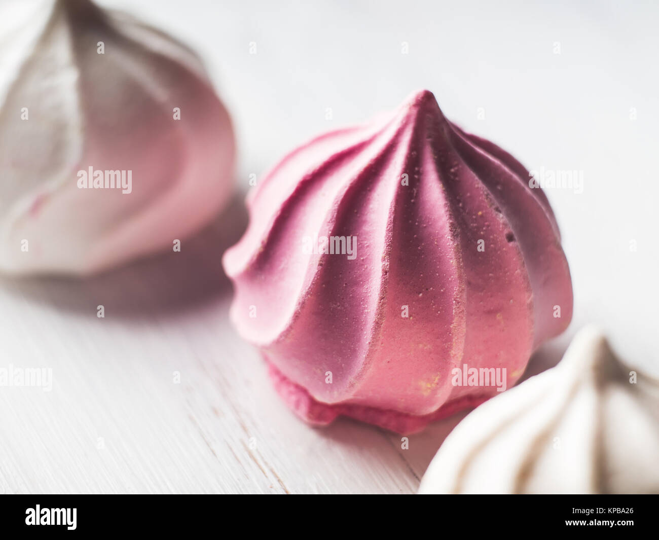 Pastel color pink and white meringue on white wooden board. Macro shot ...