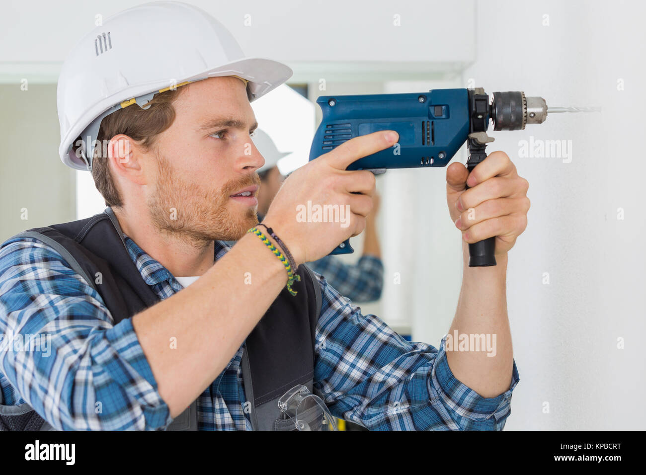 young handsome handyman using a drill at work Stock Photo - Alamy
