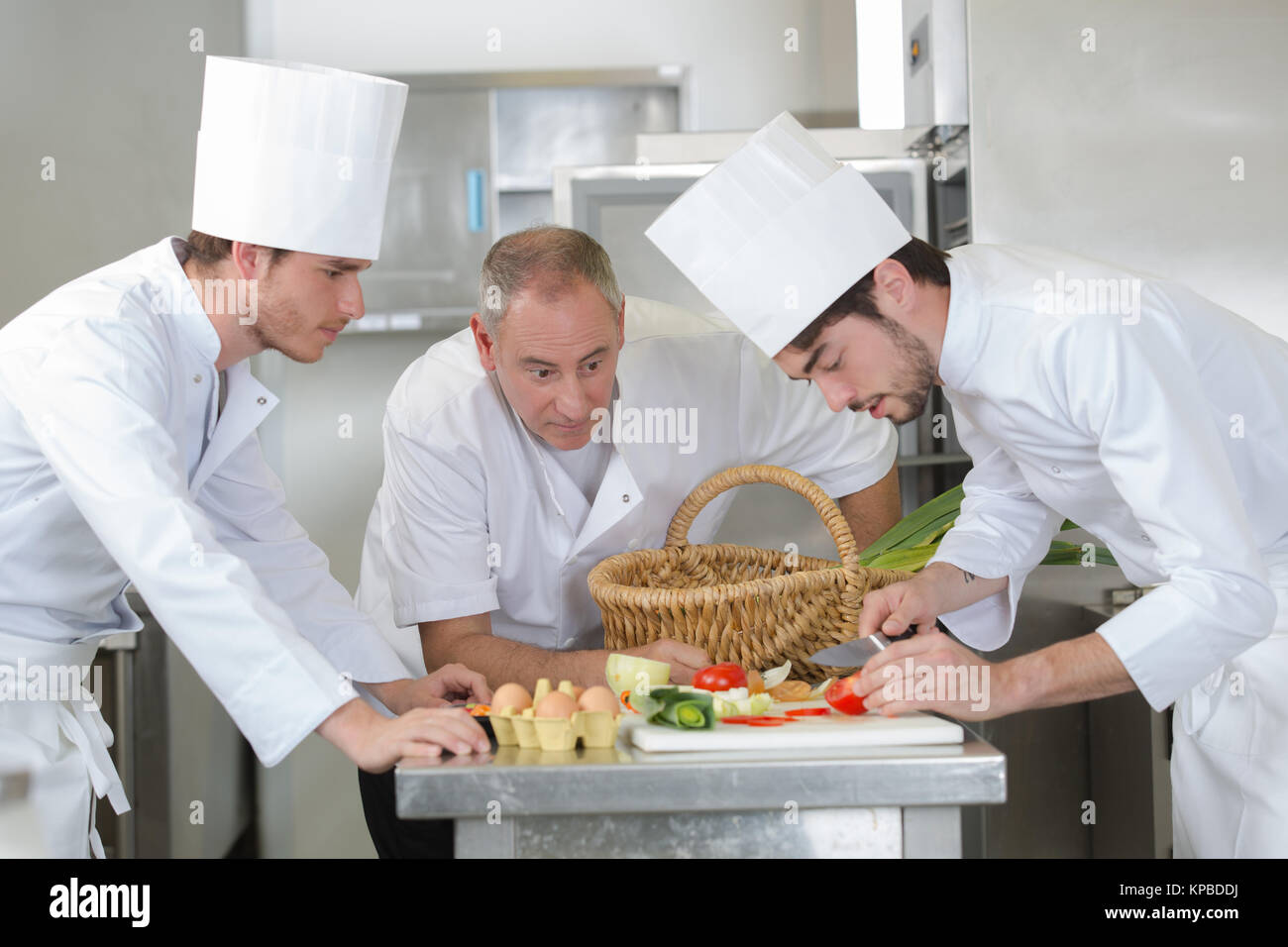 chief chef watching his assistants garnishing a dish Stock Photo - Alamy