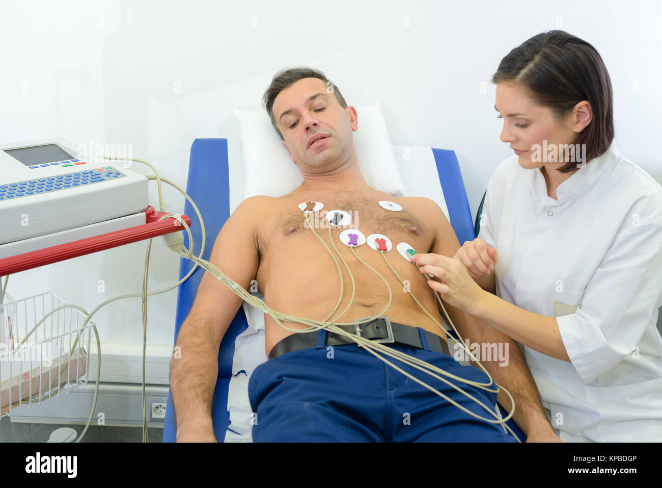 Nurse sticking heart monitor pads onto patient Stock Photo - Alamy