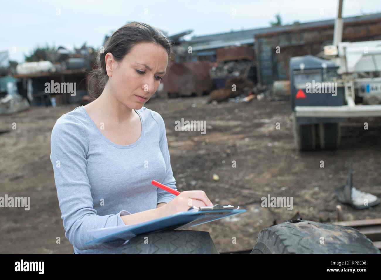 rural female technician writing reading of meter on clipboard outdoors ...