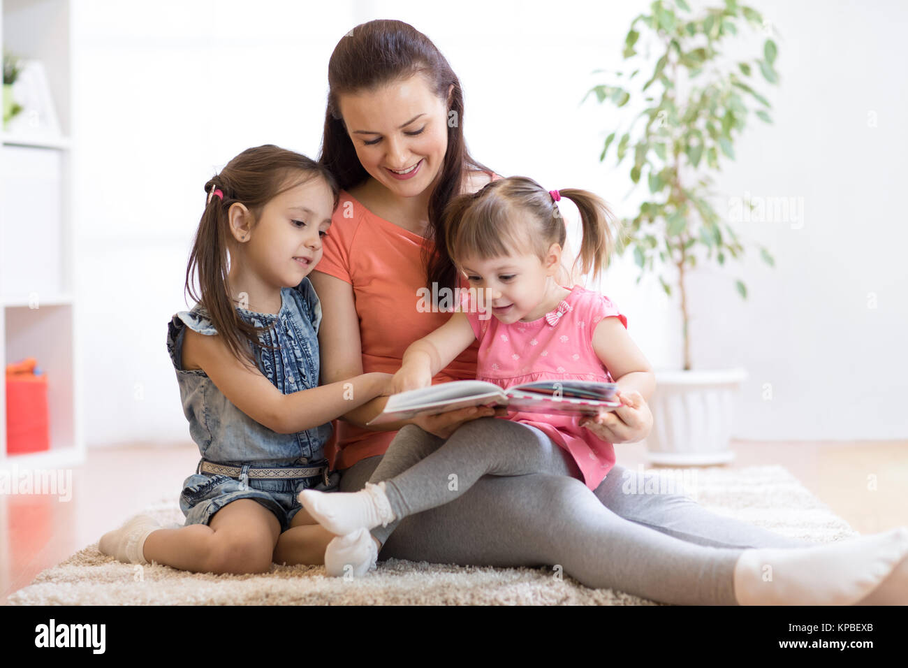 pretty mother reading book to her daughters Stock Photo - Alamy