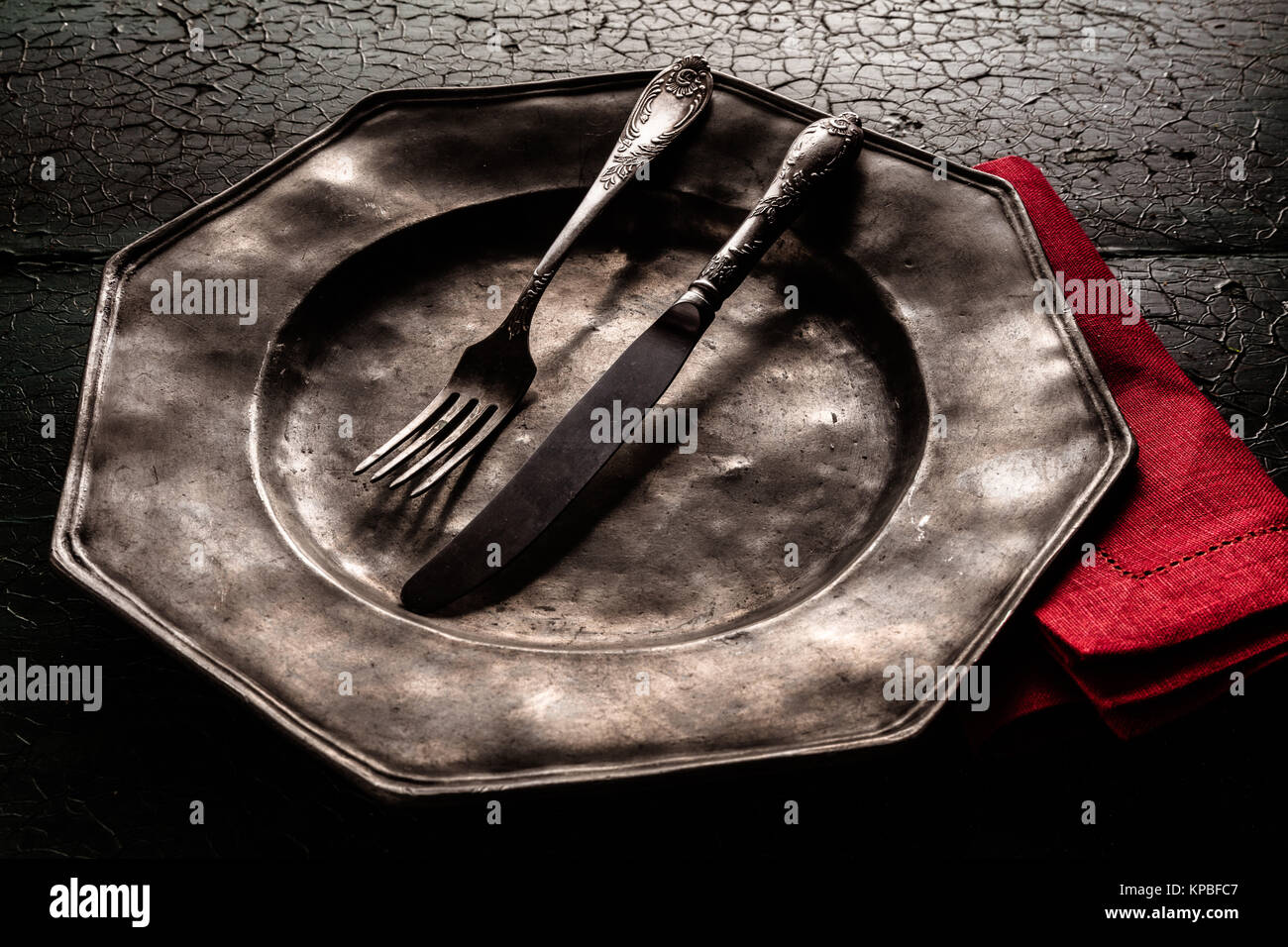 Old rustic vintage octagonal pewter plate with eating utensils and a ...