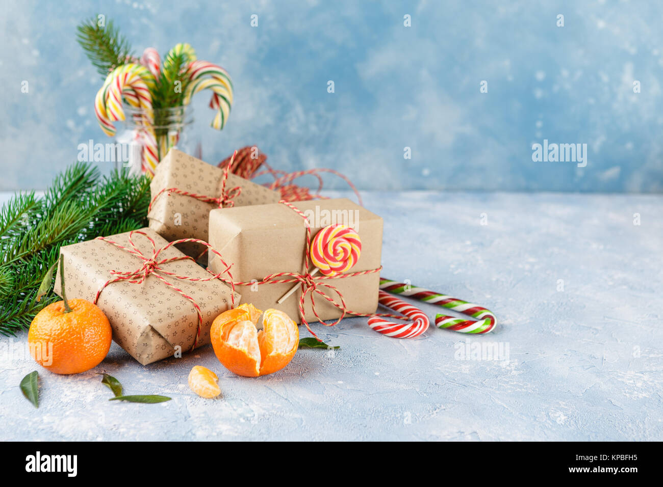 Gift boxes in kraft paper, fresh tangerines with leaves, candy canes ...
