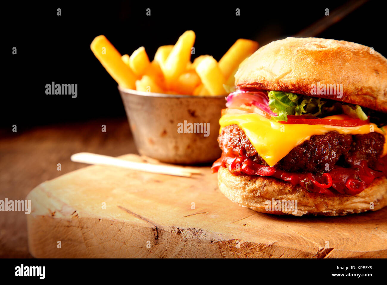 Cheeseburger and french fries on a countertop on old wooden background ...