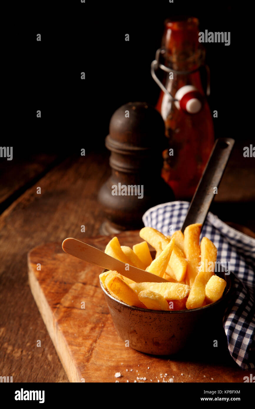 Crispy golden potato chips or French Fries in a rustic metal container ...