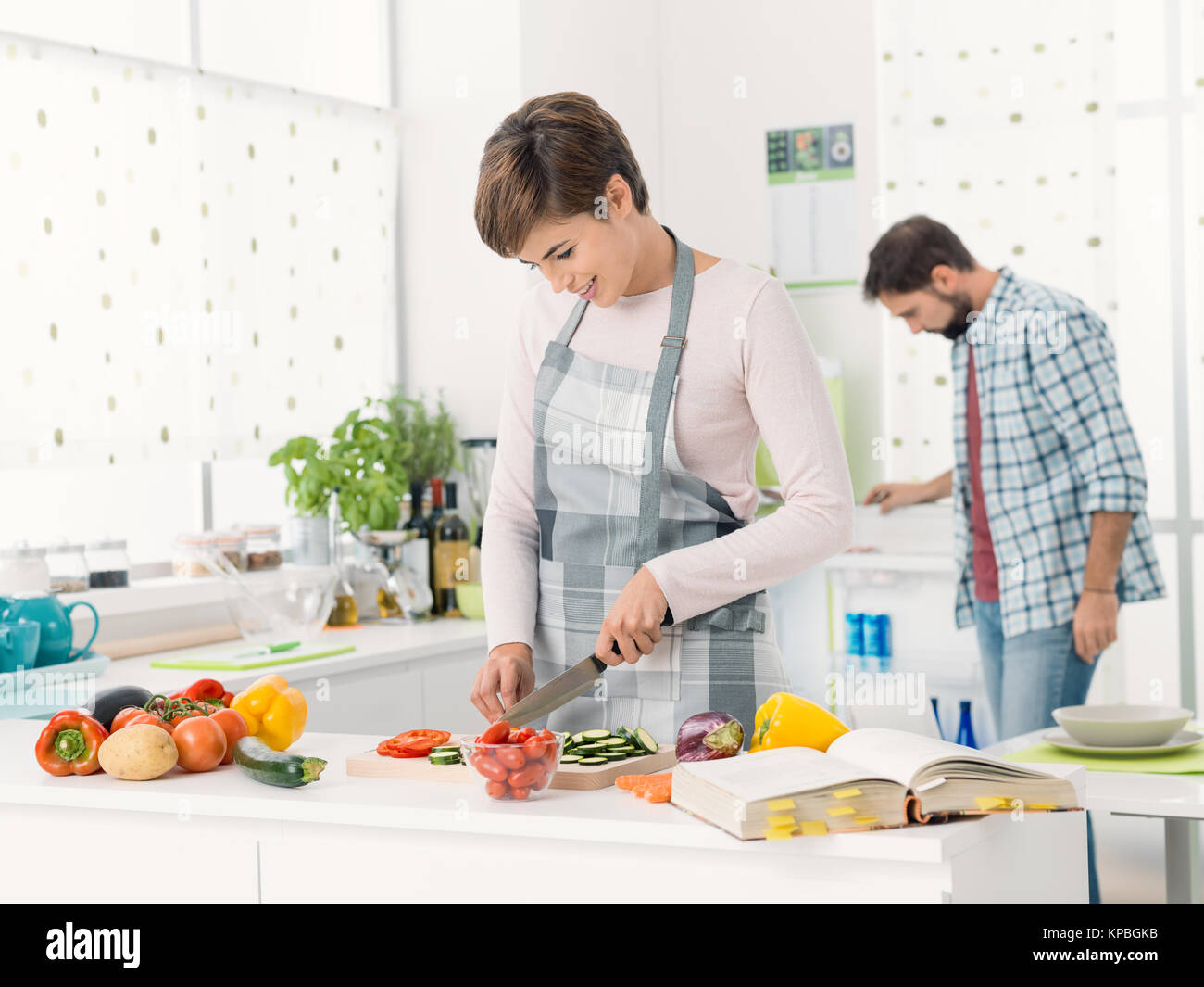 Couple preparing lunch together at home in the kitchen: the woman is ...