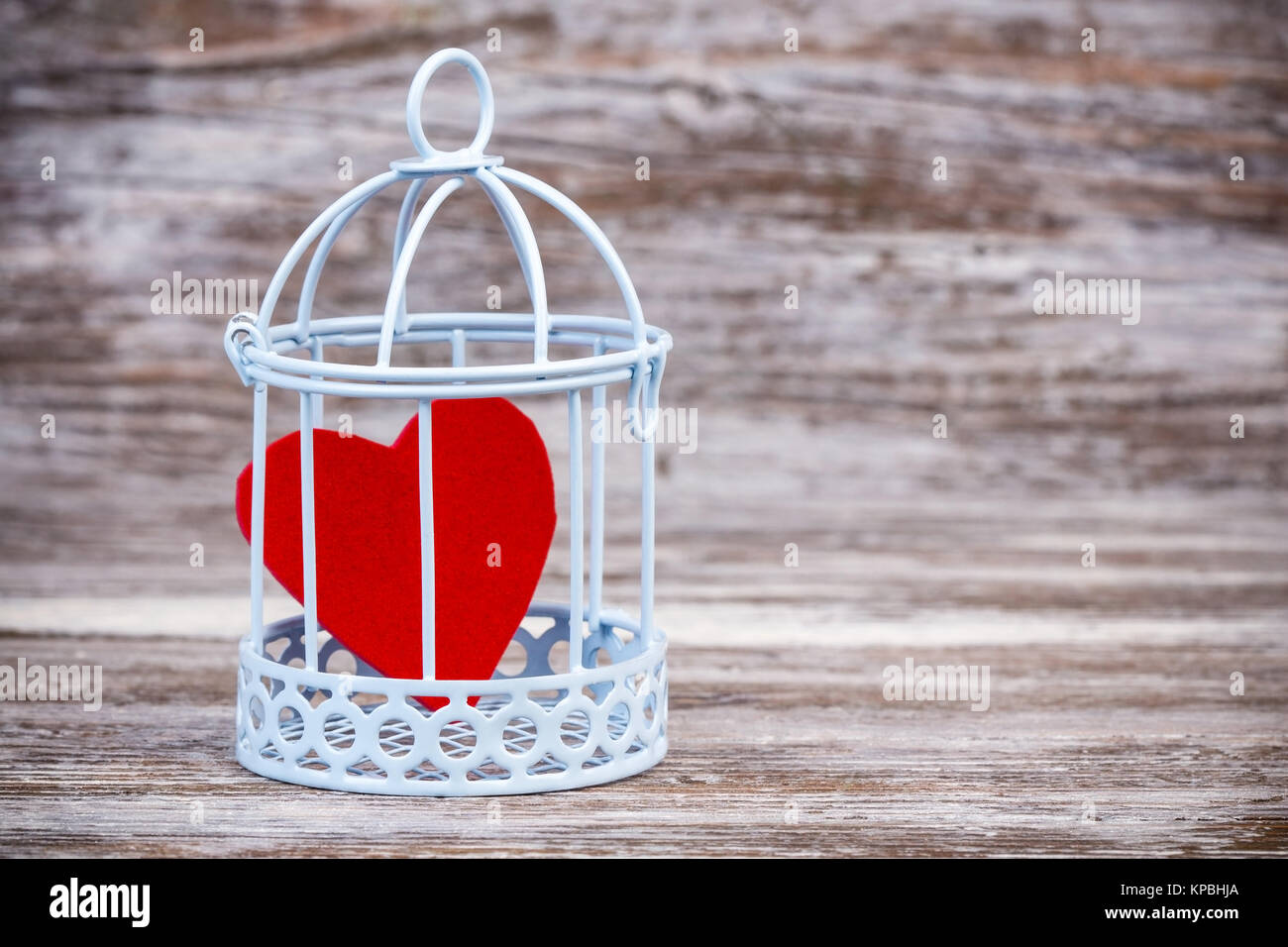 Heart in cage with wooden background Stock Photo - Alamy