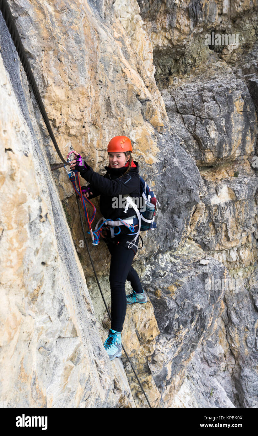 young female on a narrow and exposed ledge of a Via Ferrata in the ...