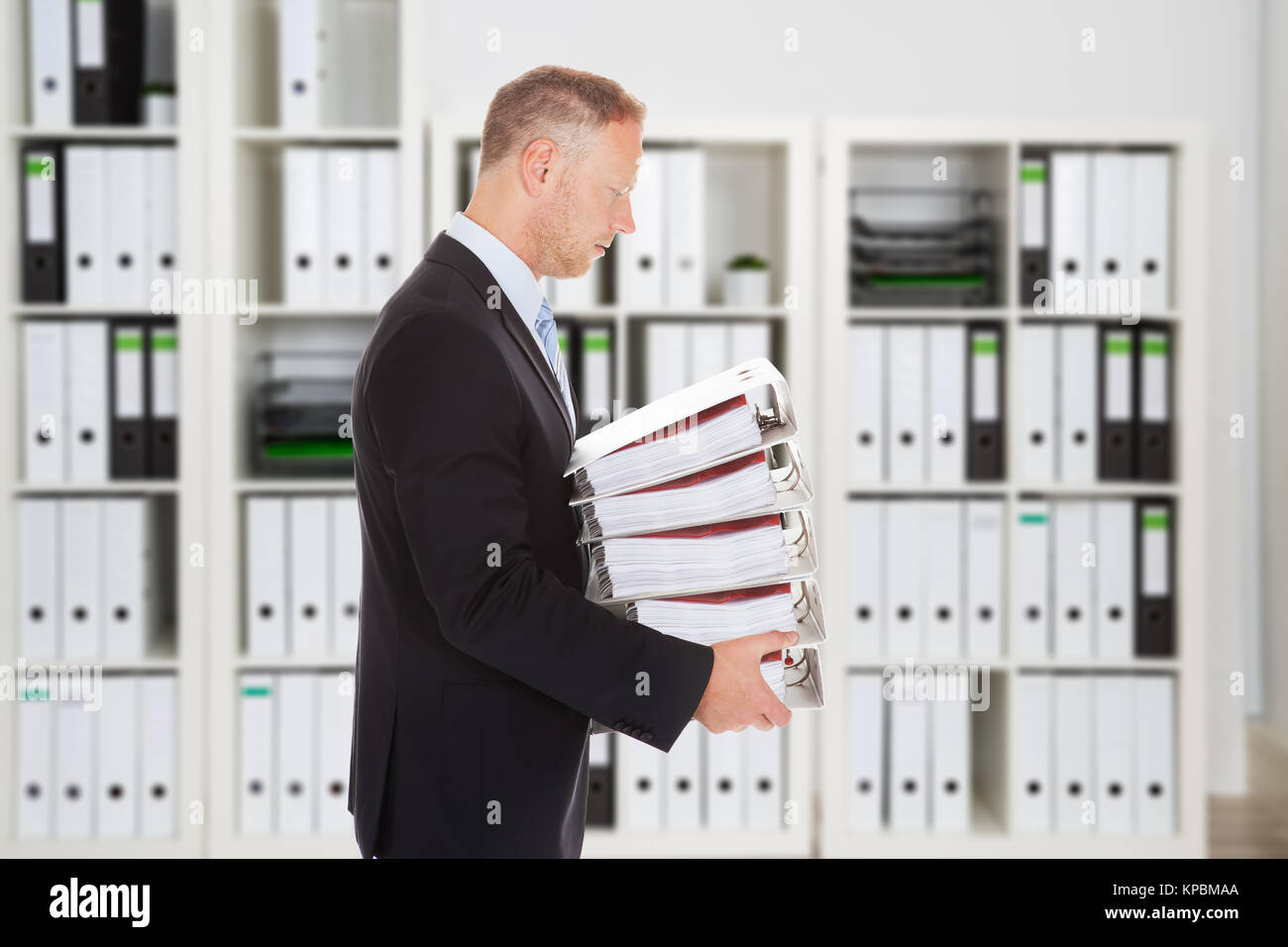 Mid Adult Businessman Carrying Binders In Office Stock Photo - Alamy