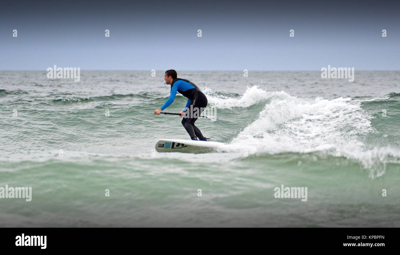 Man in wetsuit stand-up paddleboarding on wave in Dingle, Ireland Stock ...