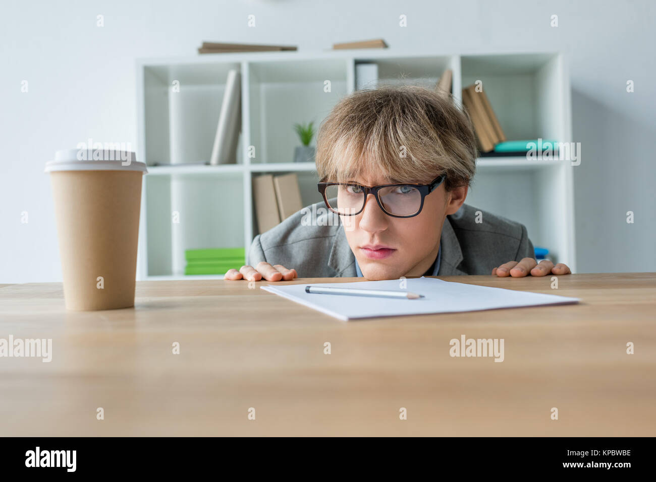 Tired businessman leaning on table Stock Photo - Alamy