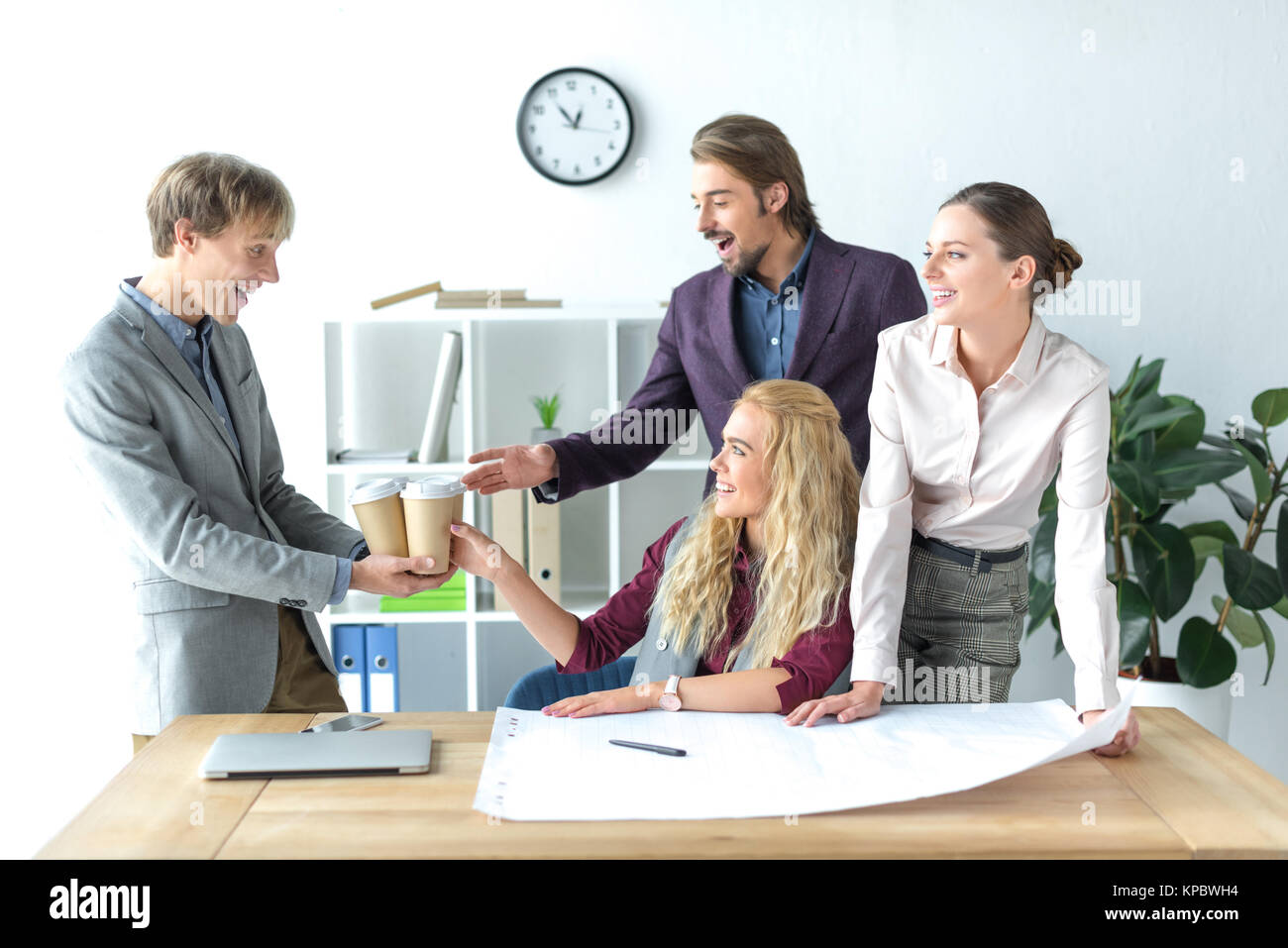 Happy businesswomen with disposable coffee cups sharing secrets against ...