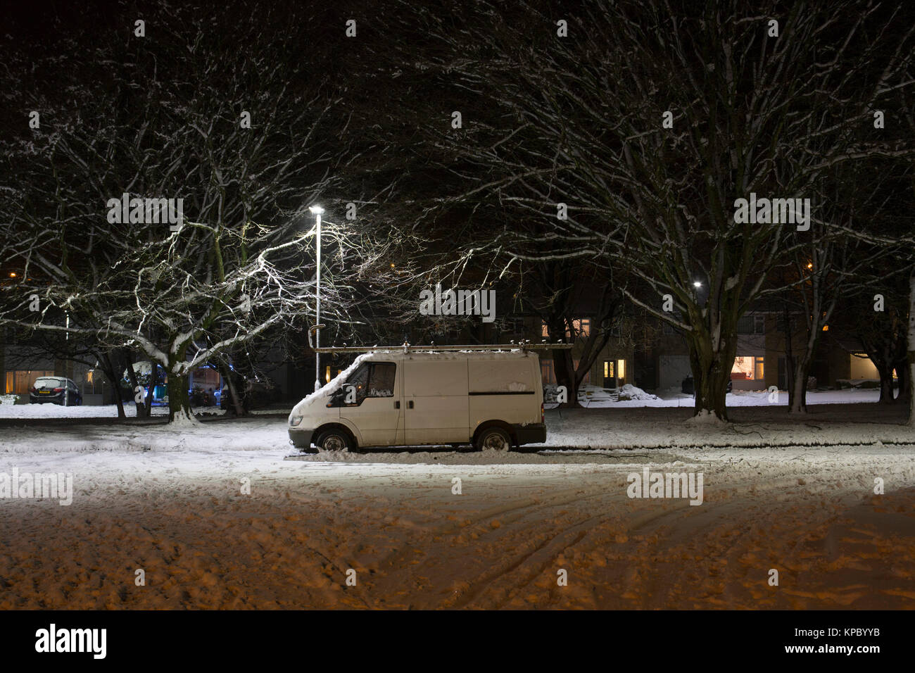 A van parked on the side of a road covered in a fall of winter snow ...