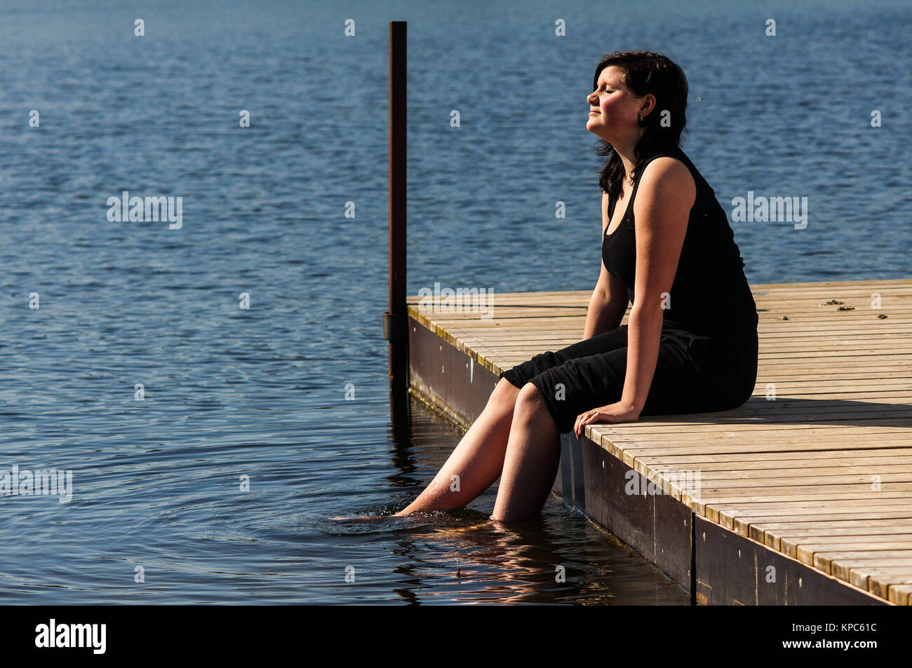 young lady sitting on the jetty Stock Photo - Alamy