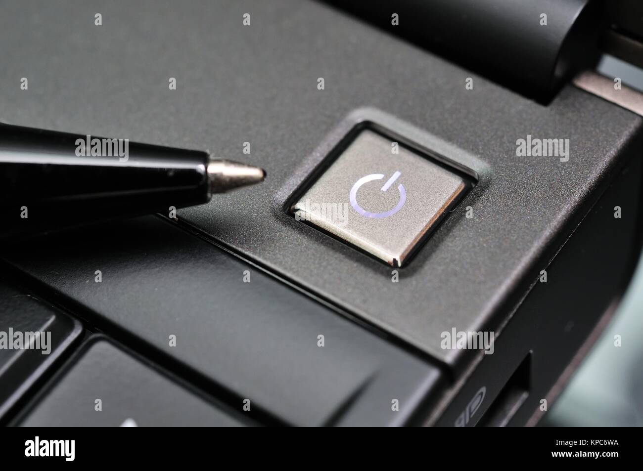 Black pen pointing to lighted up power button on computer Stock Photo ...