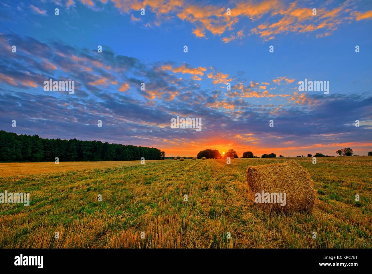 sunset over hay bales field Stock Photo - Alamy
