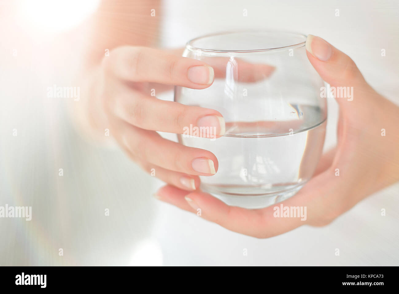 Female hands holding a clear glass of water. Slime body on background ...