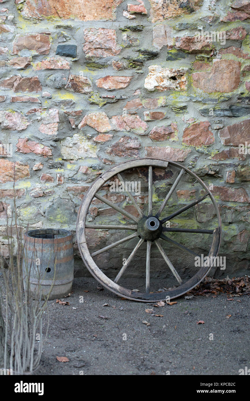 old wagon wheel and barrel made of wood on a stone wall Stock Photo - Alamy
