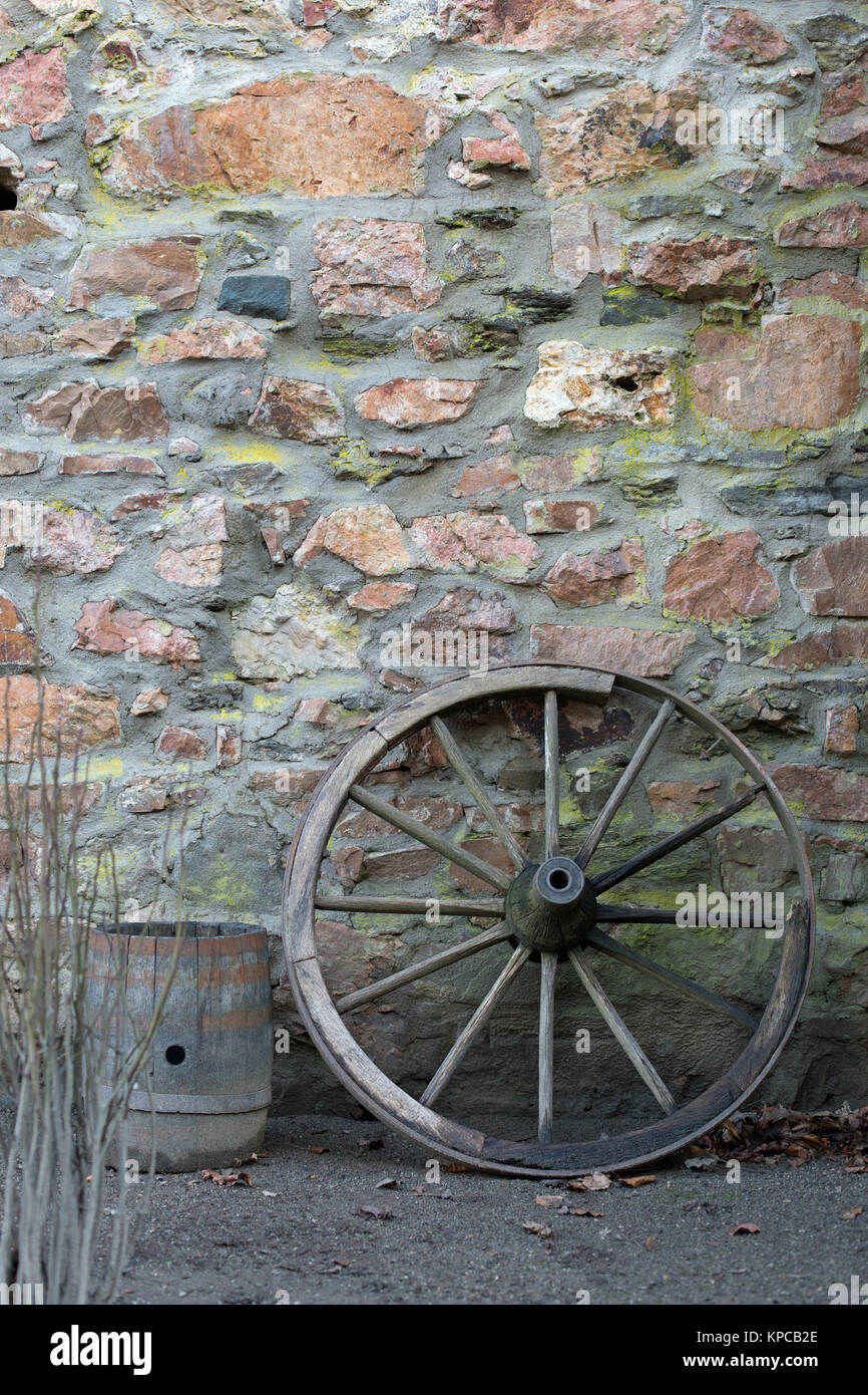 old wagon wheel and barrel made of wood on a stone wall Stock Photo - Alamy