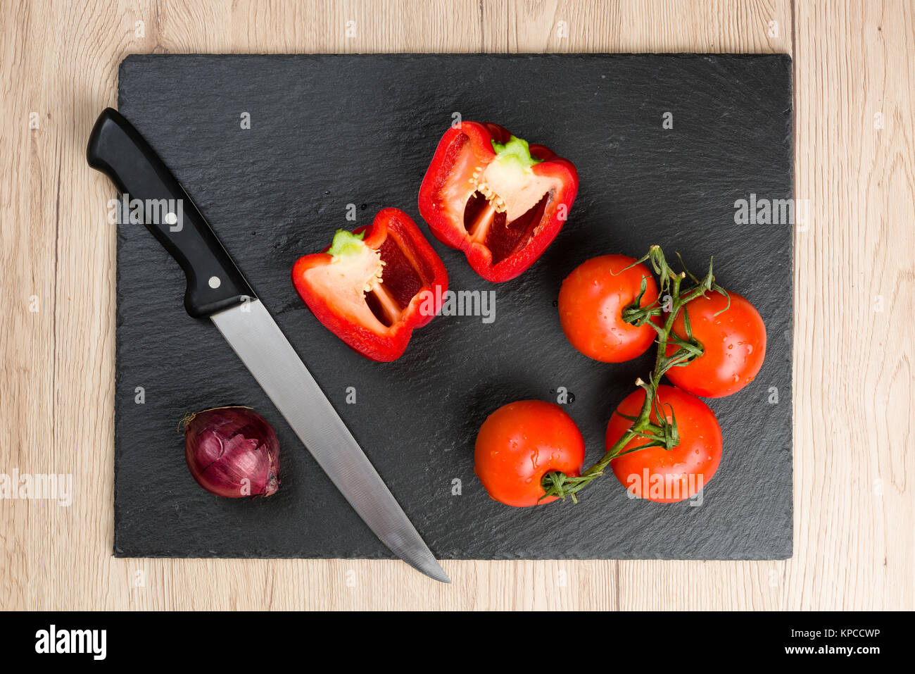 Black slate cutting board with knife and vegetables, ready for slicing ...