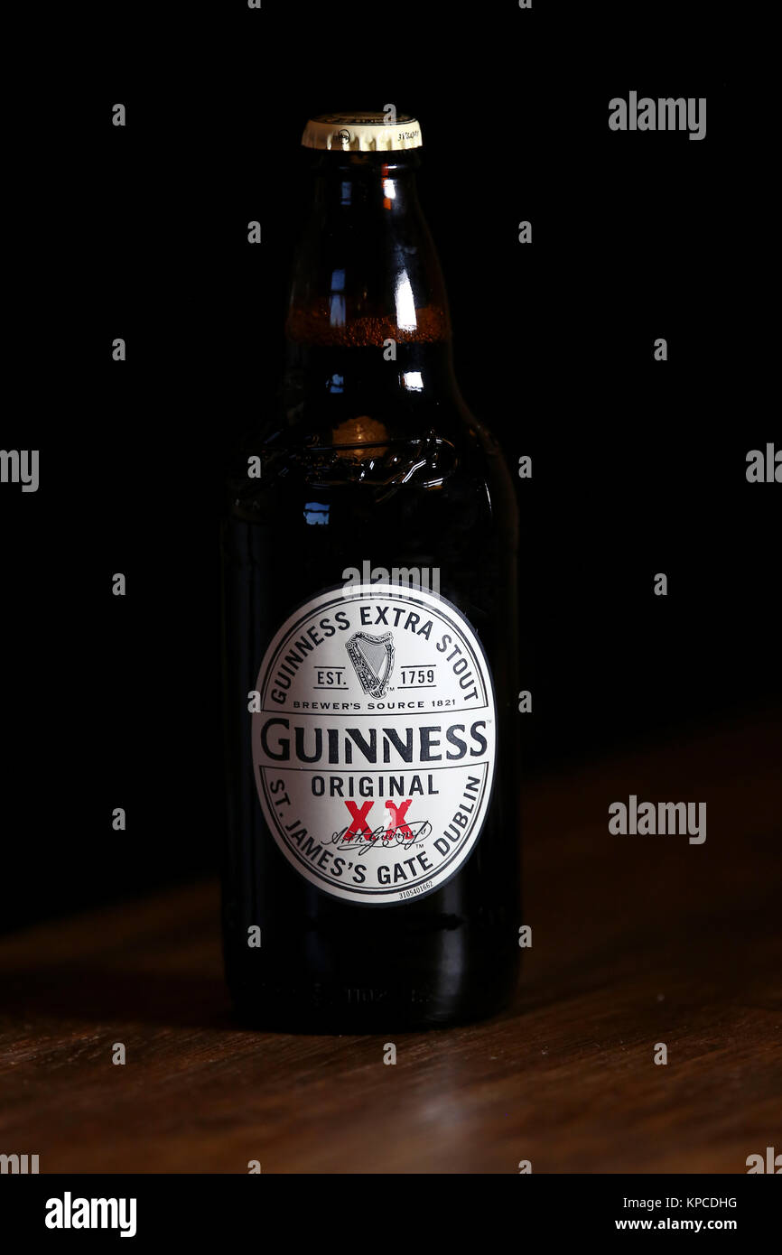 A bottle of Guiness Original Extra Stout on a table in a pub Stock ...