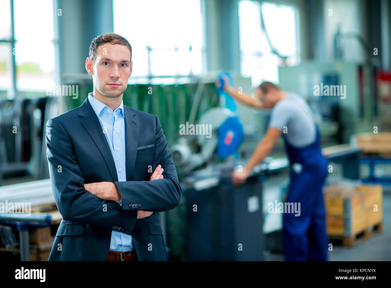 young boss with worke in the background in his factory Stock Photo - Alamy