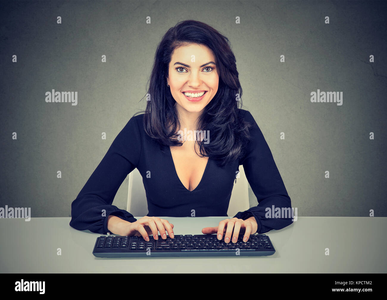 Excited young model typing on computer keyboard looking forward and ...