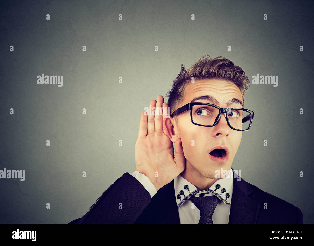 Young neat man in eyeglasses interested in gossip listening to ...