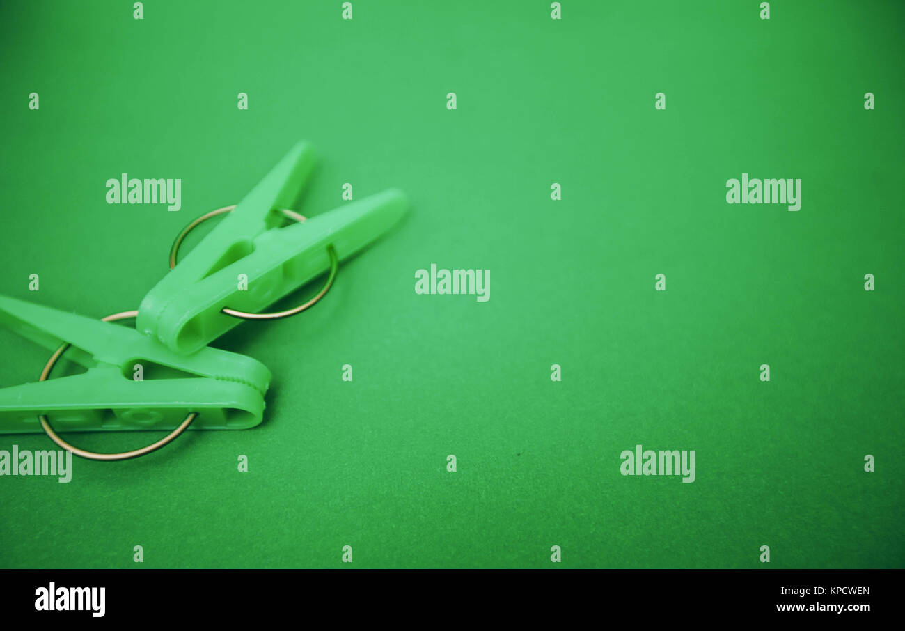Green plastic clothes clothes pegs on a bright one-color green ...