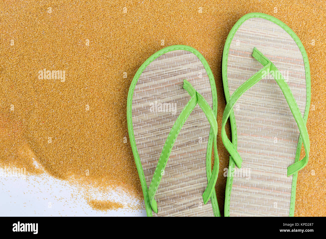 Green flip flips on sand for background Stock Photo - Alamy