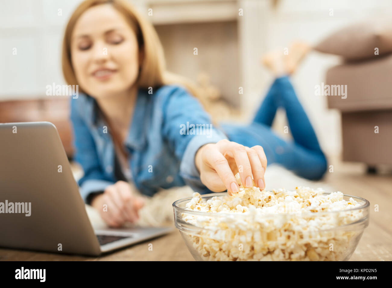 Gleeful woman eating popcorn on the floor Stock Photo - Alamy