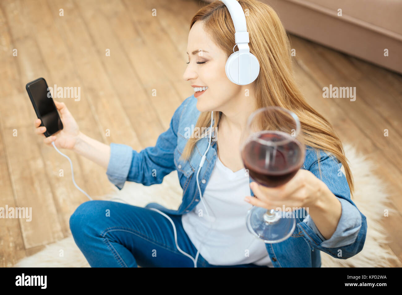Cheerful woman drinking and singing on the floor Stock Photo - Alamy