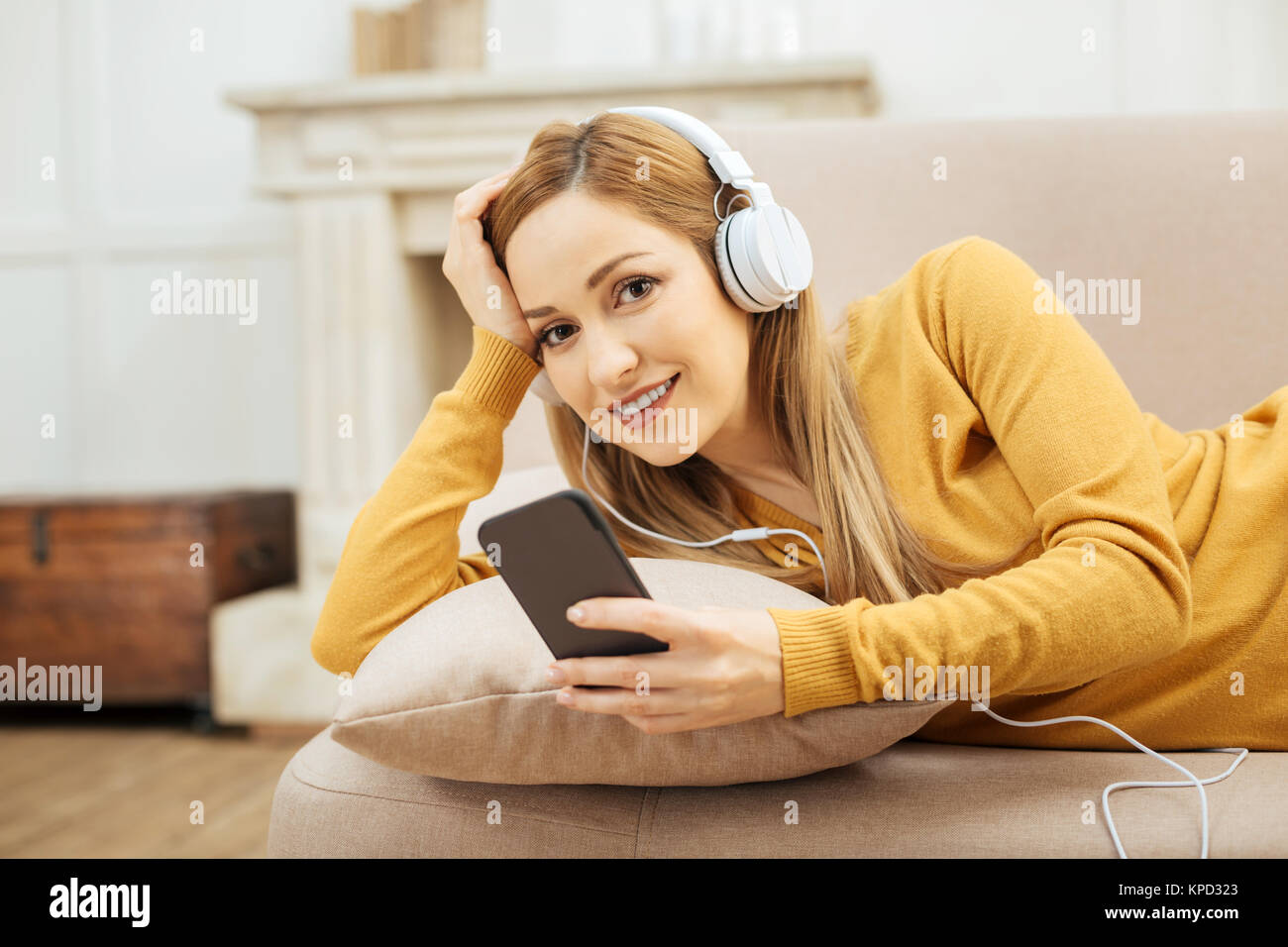 Cheerful woman relaxing on the sofa and listening to music Stock Photo ...