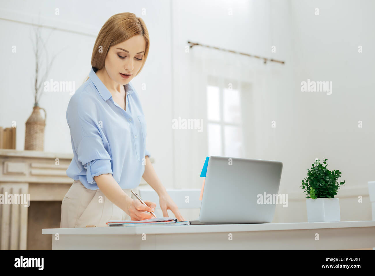 Serious woman working and writing information down Stock Photo - Alamy