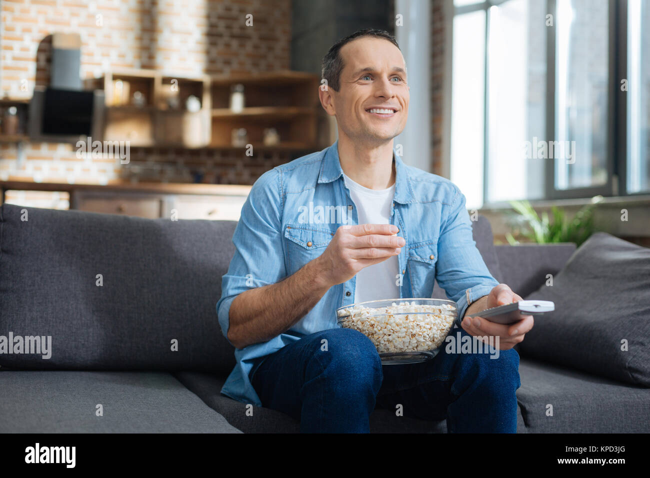 Happy young man watching interesting program Stock Photo - Alamy
