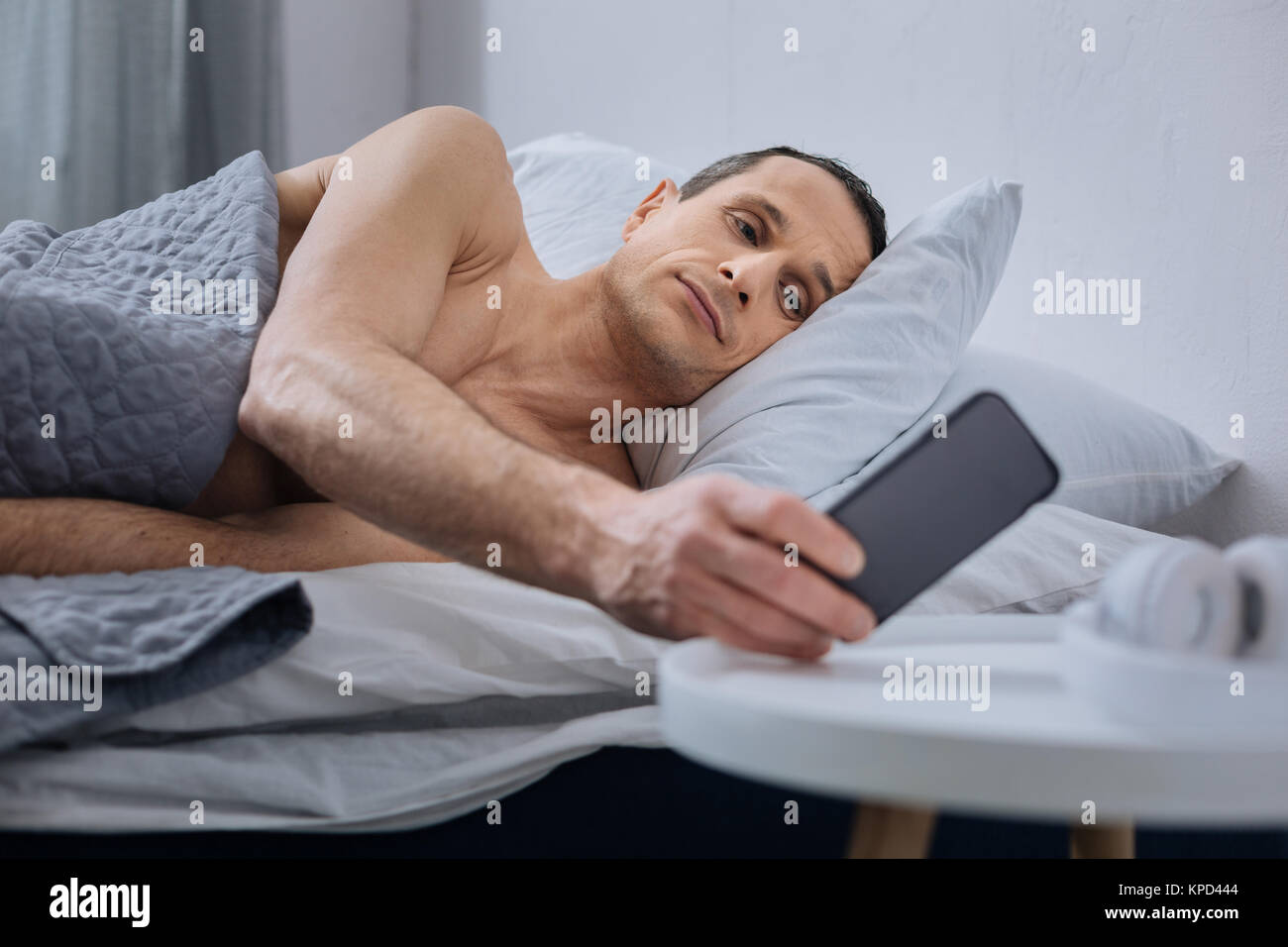 Attentive freelancer checking time on smartphone Stock Photo - Alamy
